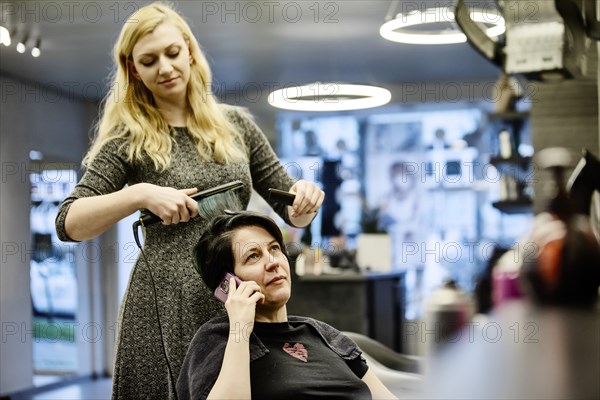 Hairdresser does the hair of a customer on the phone in a hairdressing ...