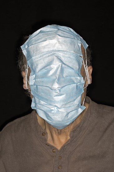 Male head with 4 blue surgical masks completely covered from the front ...