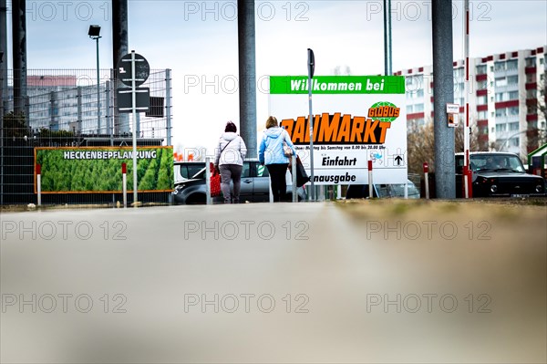 Two woman at the entrance of a Globus DIY store in a commercial area in ...