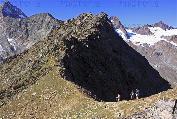 Three mountain walkers hiking over mountain ridge in the mountains of ...