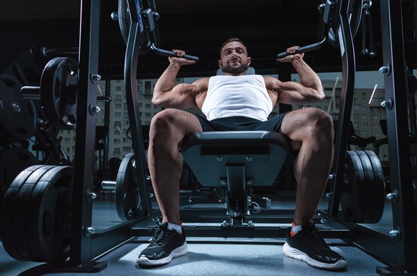 Handsome young man pumps his shoulders in a special machine. Fitness ...