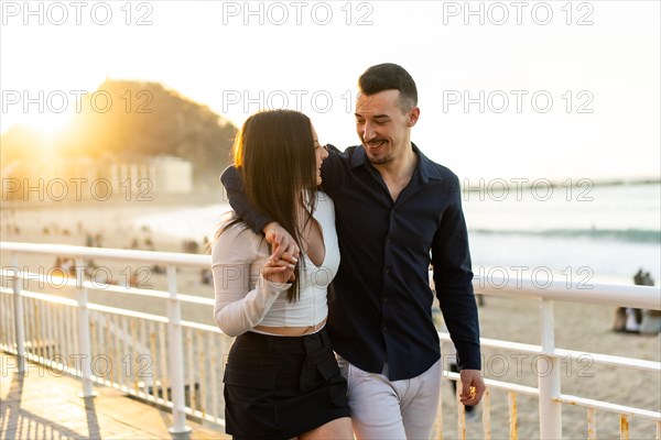 Romantic couple embracing looking at each other walking along a ...