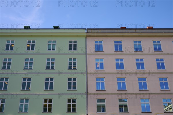 Two neighbouring buildings with green and pink facades under a blue sky ...